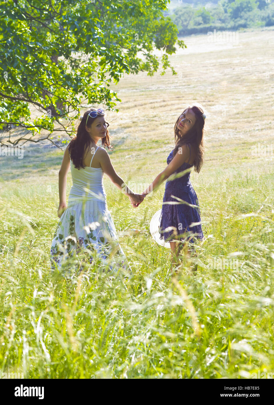 happy girls in a green field holding each other's hand Stock Photo - Alamy