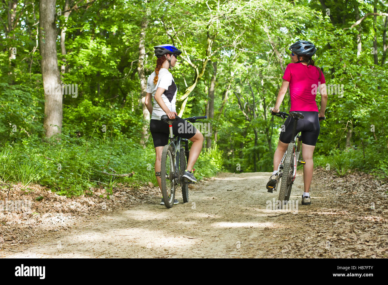 two girls riding the bicycle in the forest Stock Photo - Alamy