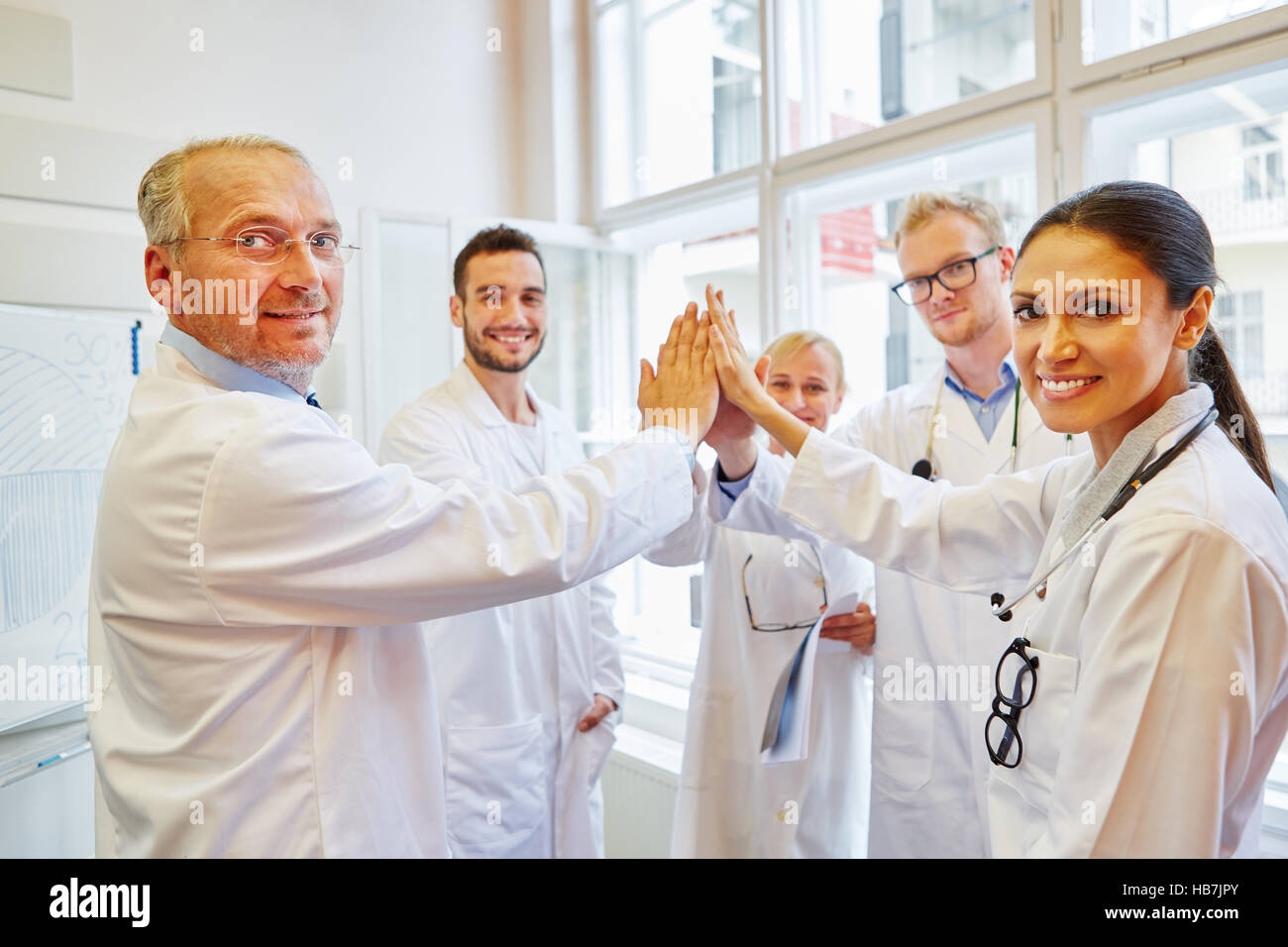Group of doctors as successful team giving High Five Stock Photo - Alamy