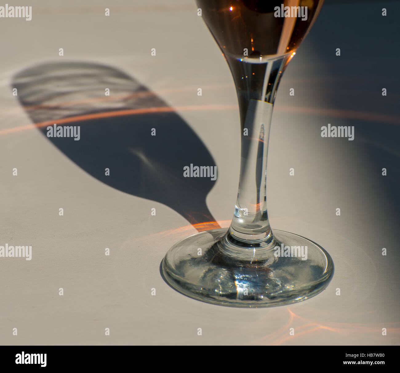 Wine glass and shadow with sun catching and reflecting circles of light ...