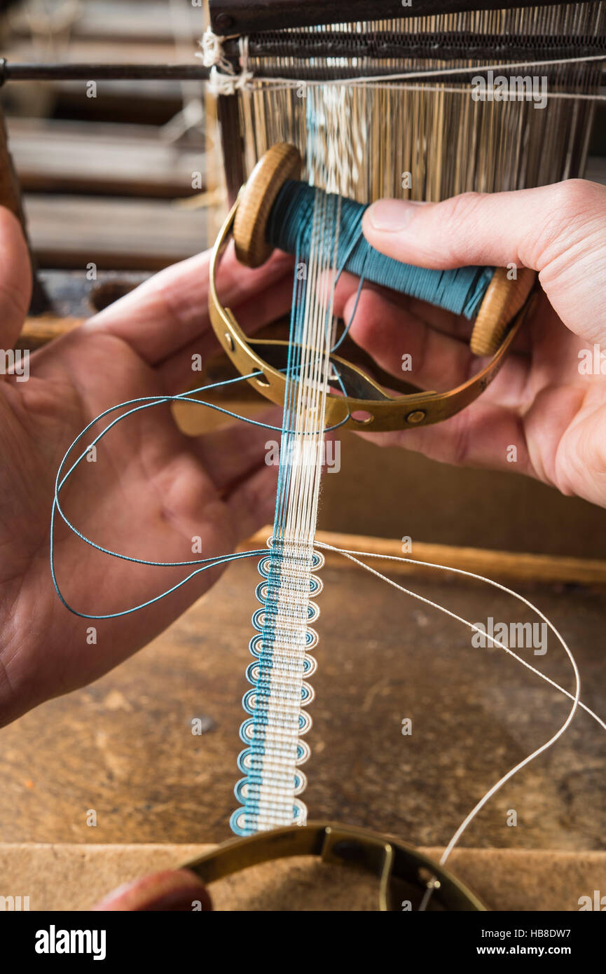 Passementerie maker, hand holding blue gimp on weaving shuttle going ...