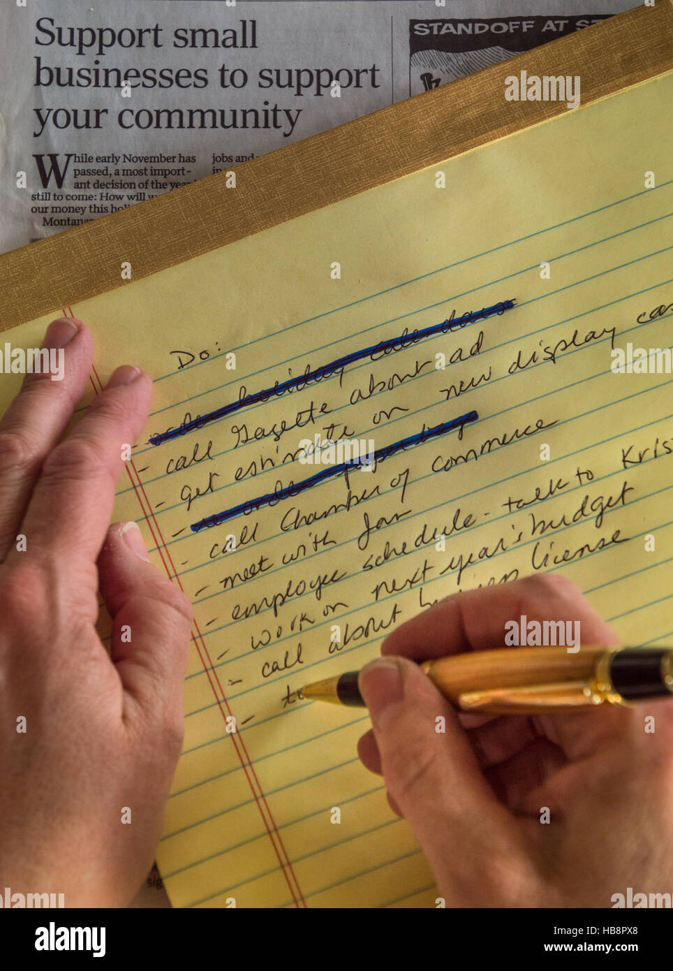 Hands adding items on a To Do list with completed tasks crossed off. A ...