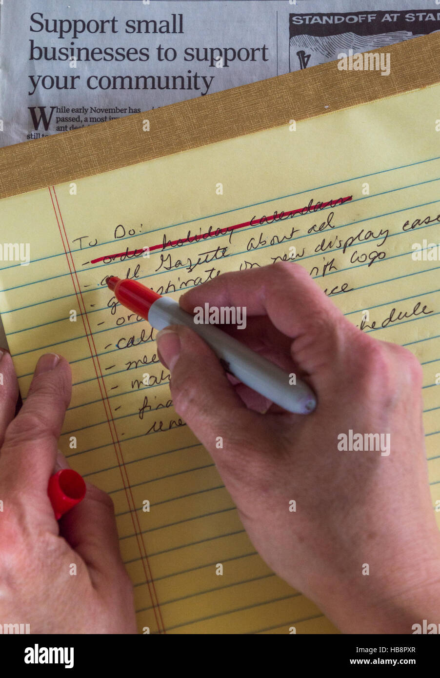 Hands crossing off completed items on a To Do list with a red marker. A ...