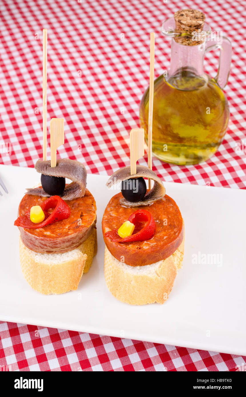 Spanish chorizo tapa with anchovies served on a checkered tablecloth ...
