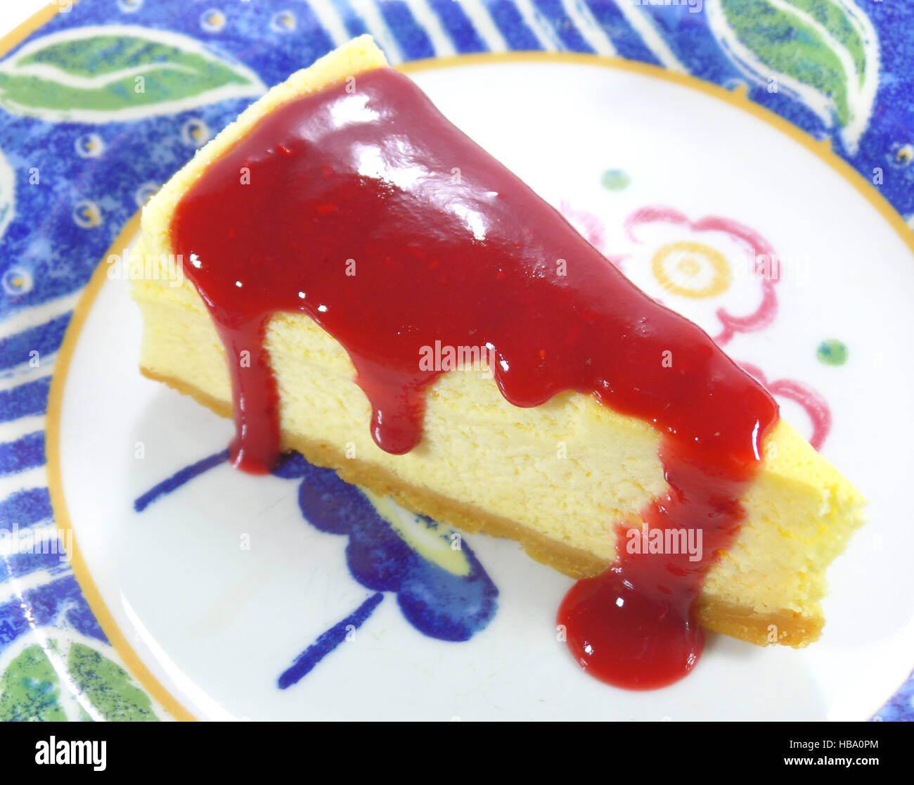 Closed up baked cheesecake with red raspberry sauce served on white and ...