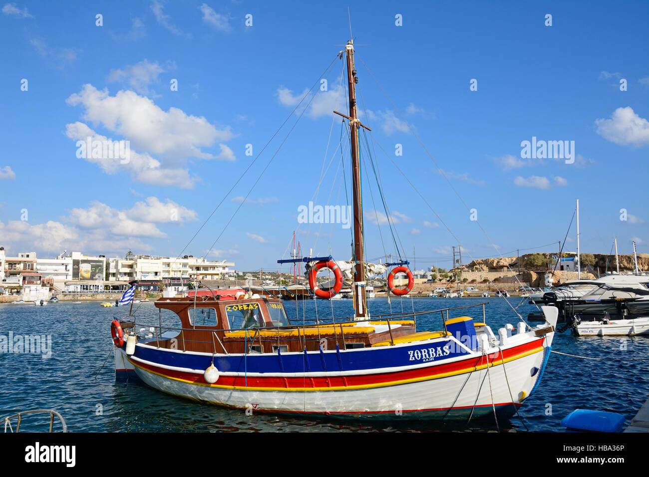 Traditional Greek yacht moored in the harbour with watefront buildings ...