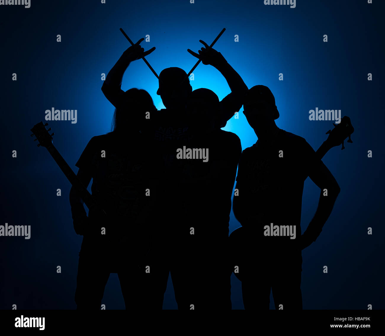 Band of young male musicians standing with instruments on a blue ...