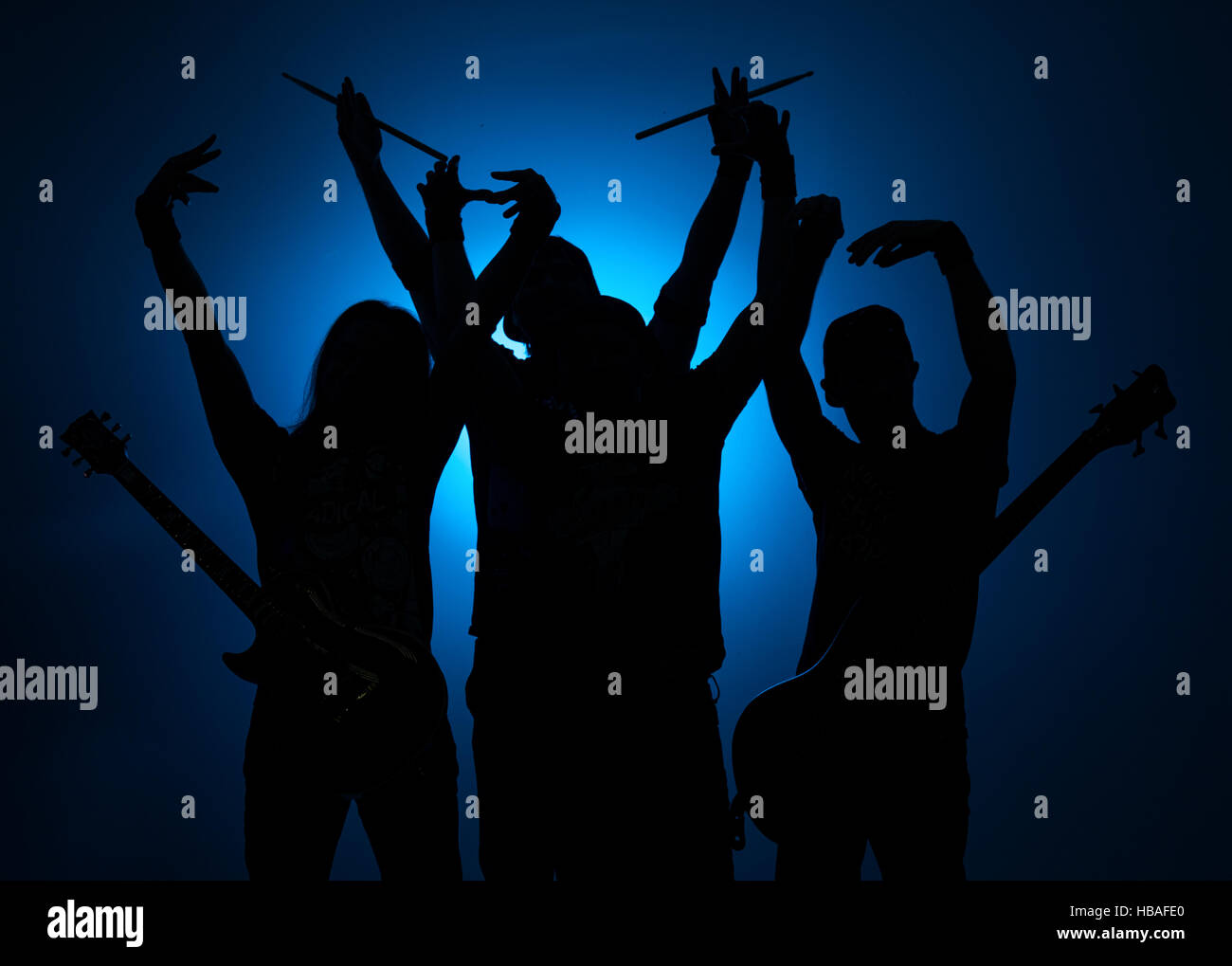 Band of young male musicians standing with instruments on a blue ...