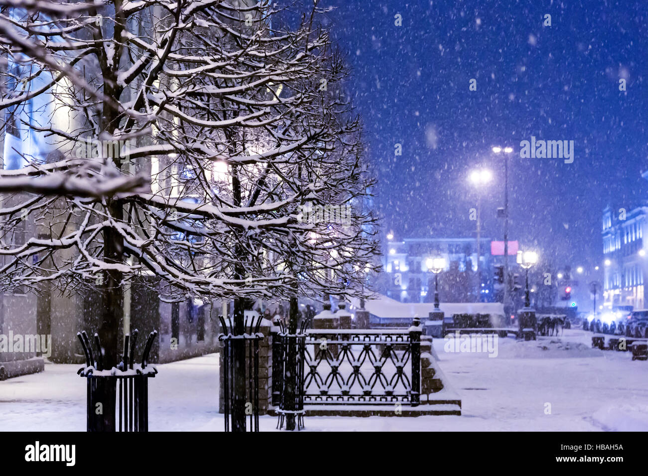 snowflakes fall down on night city covering trees, lampposts and street ...