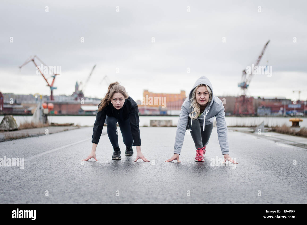 Two female running friends on their mark on dockside road Stock Photo ...