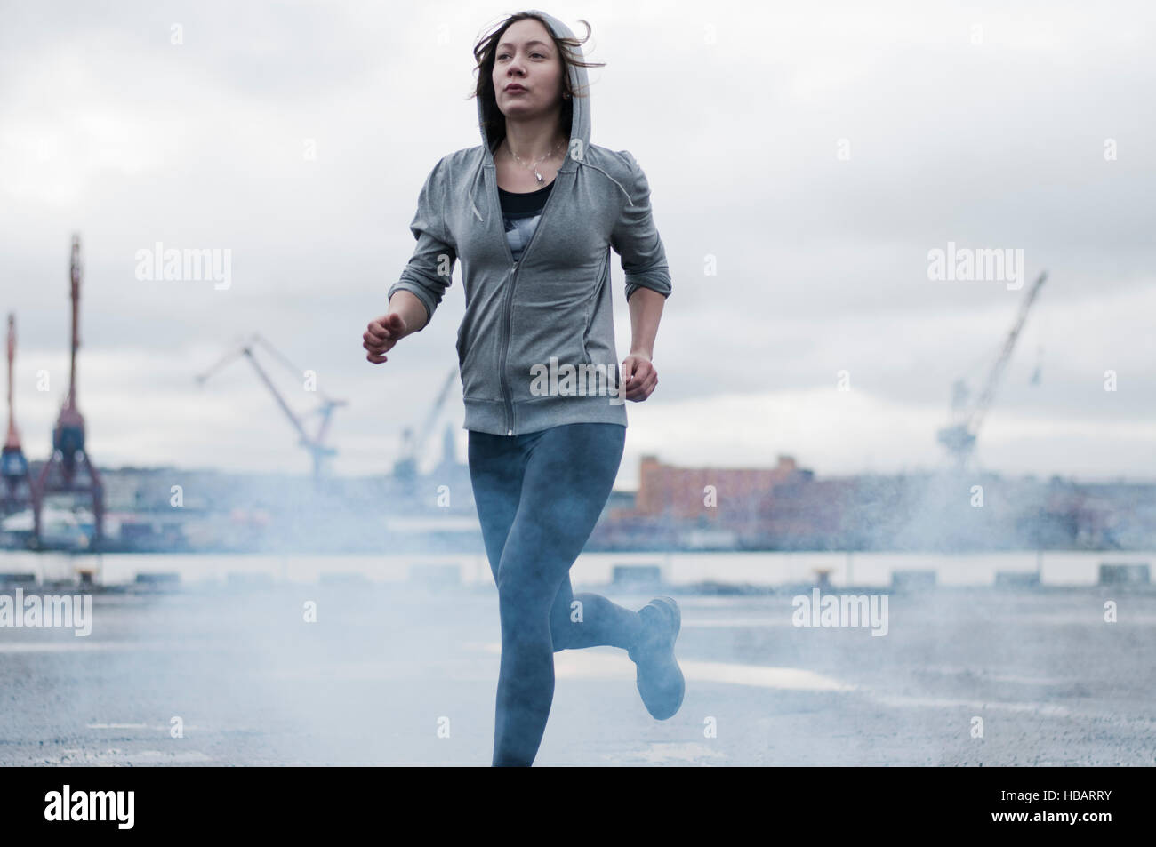 Young female runner running on stormy dockside Stock Photo - Alamy