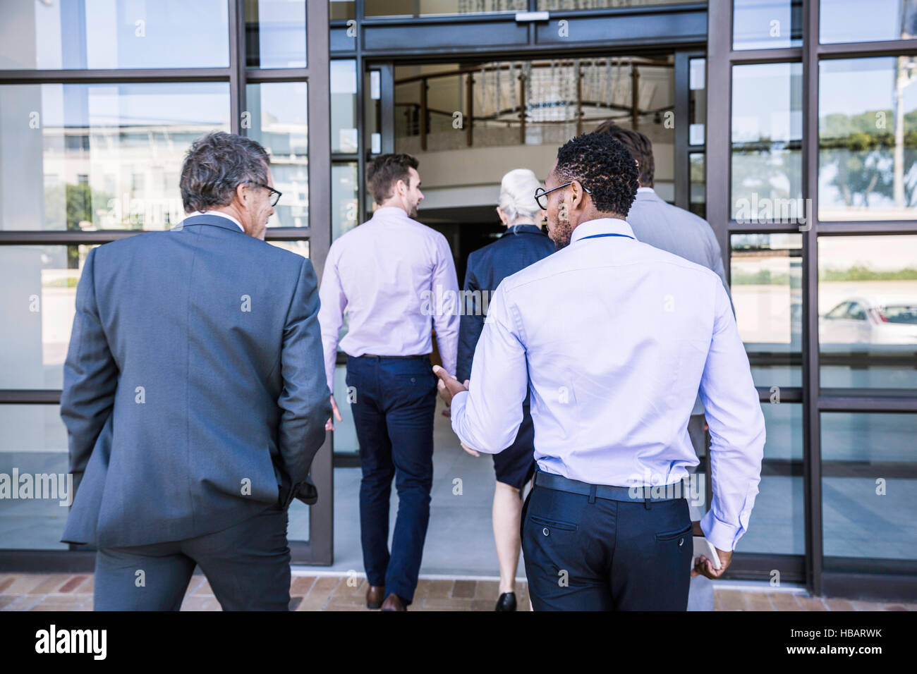 Rear view of businessmen and woman arriving at office building Stock ...