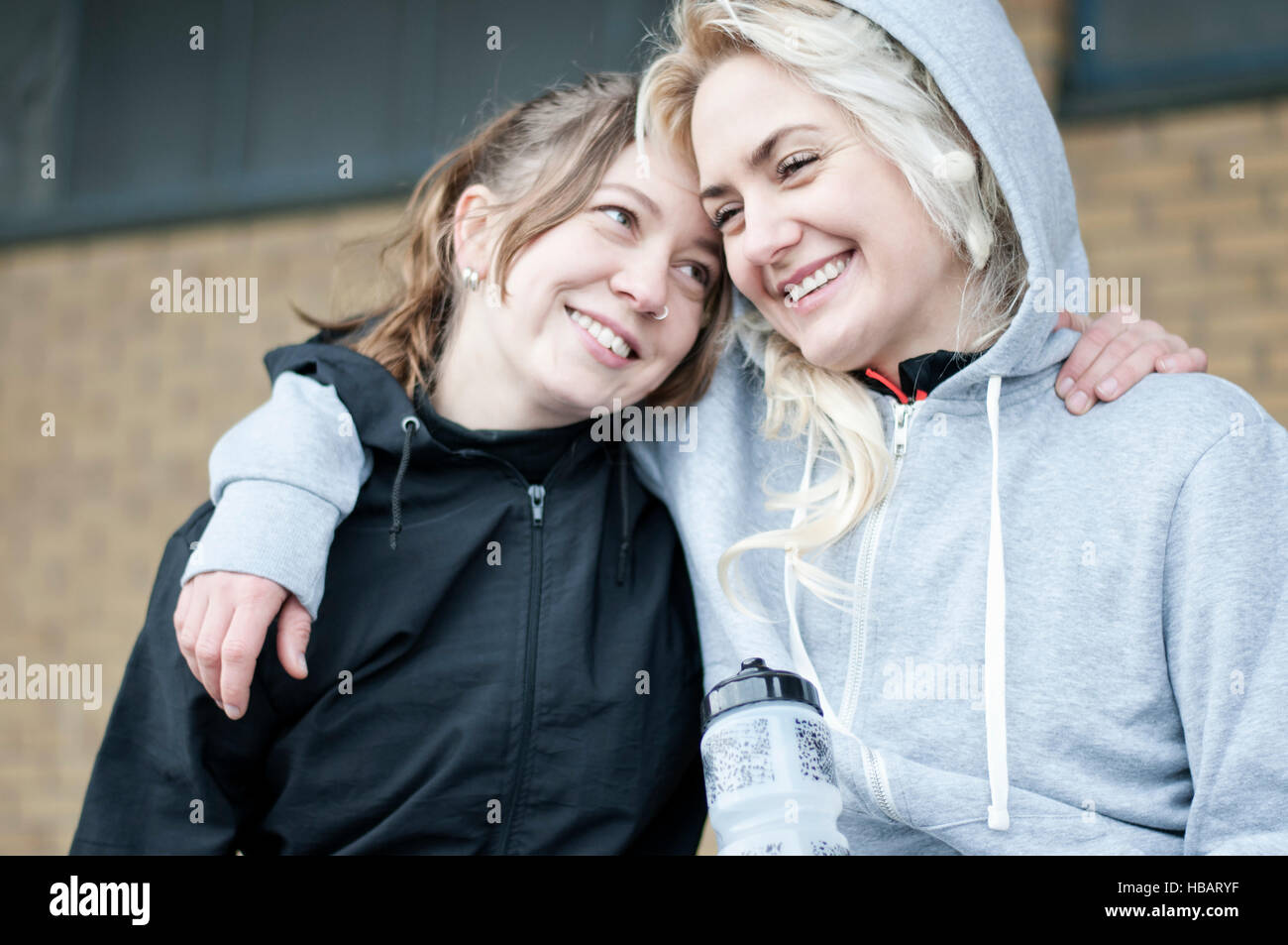 Two female running friends with arms around each other Stock Photo - Alamy