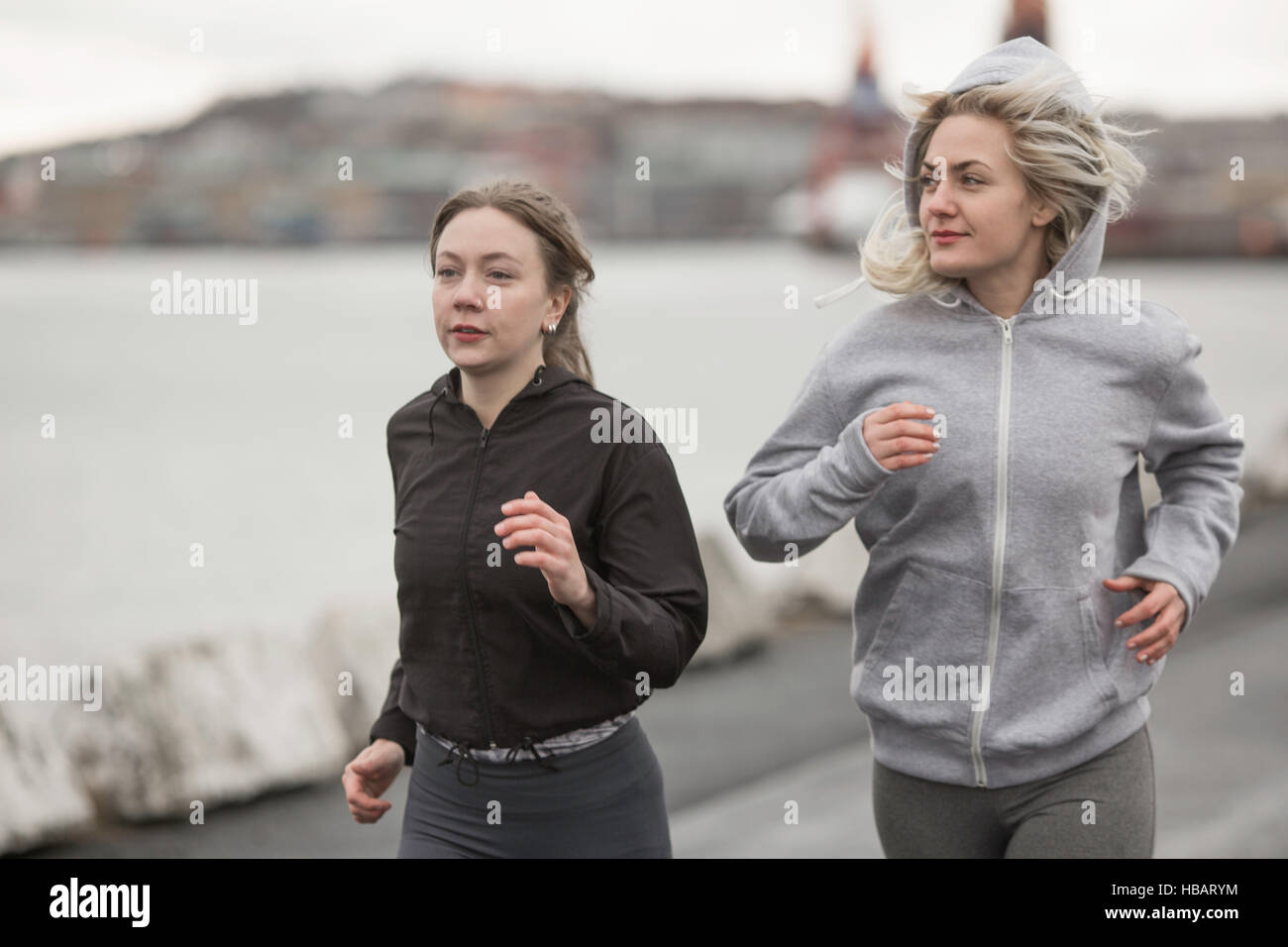 Two female runner friends running on dockside Stock Photo - Alamy