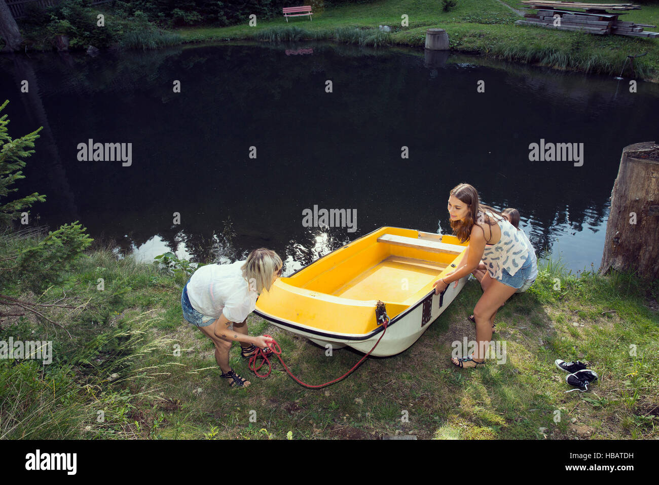 Two female friends manoeuvering rowing boat on lakeside, Sattelbergalm ...