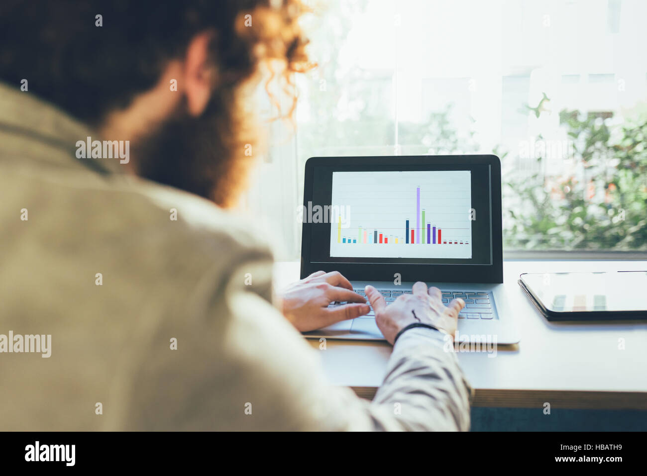 Over shoulder view of young man typing on laptop in office Stock Photo ...