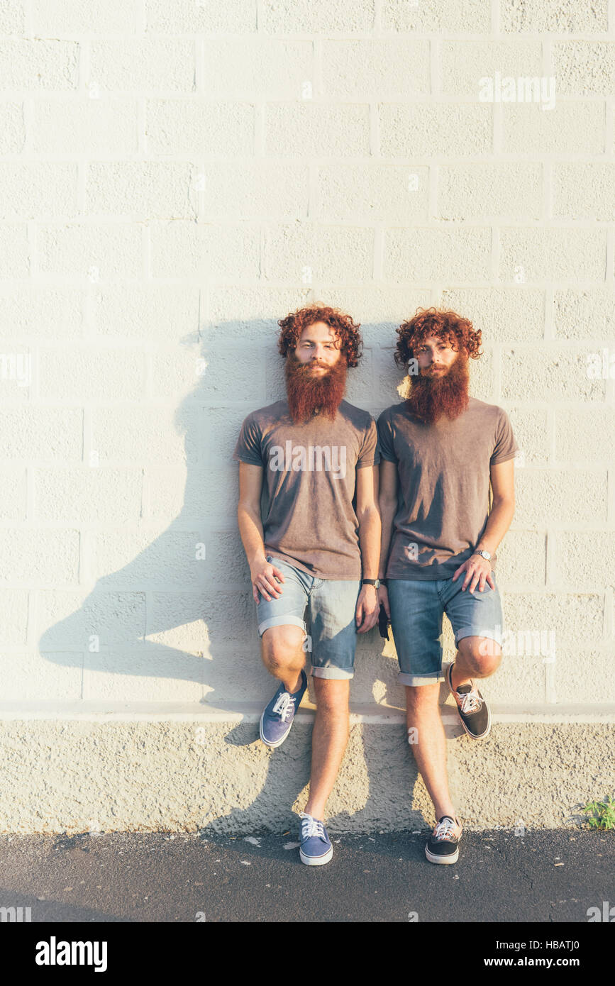 Portrait of identical adult male twins with red hair and beards against ...