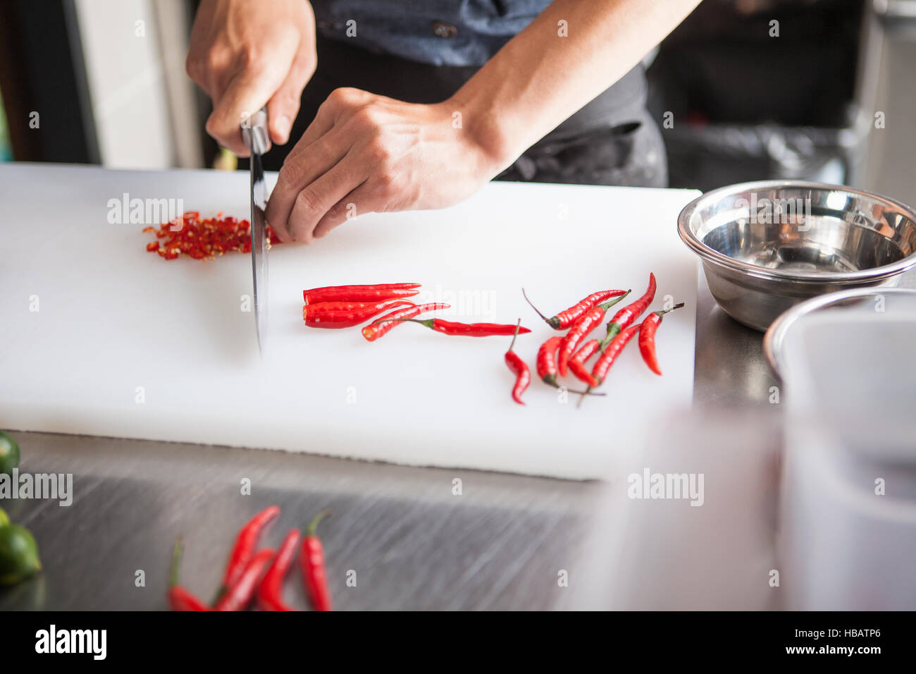 Cropped view of man slicing red chilli peppers Stock Photo - Alamy