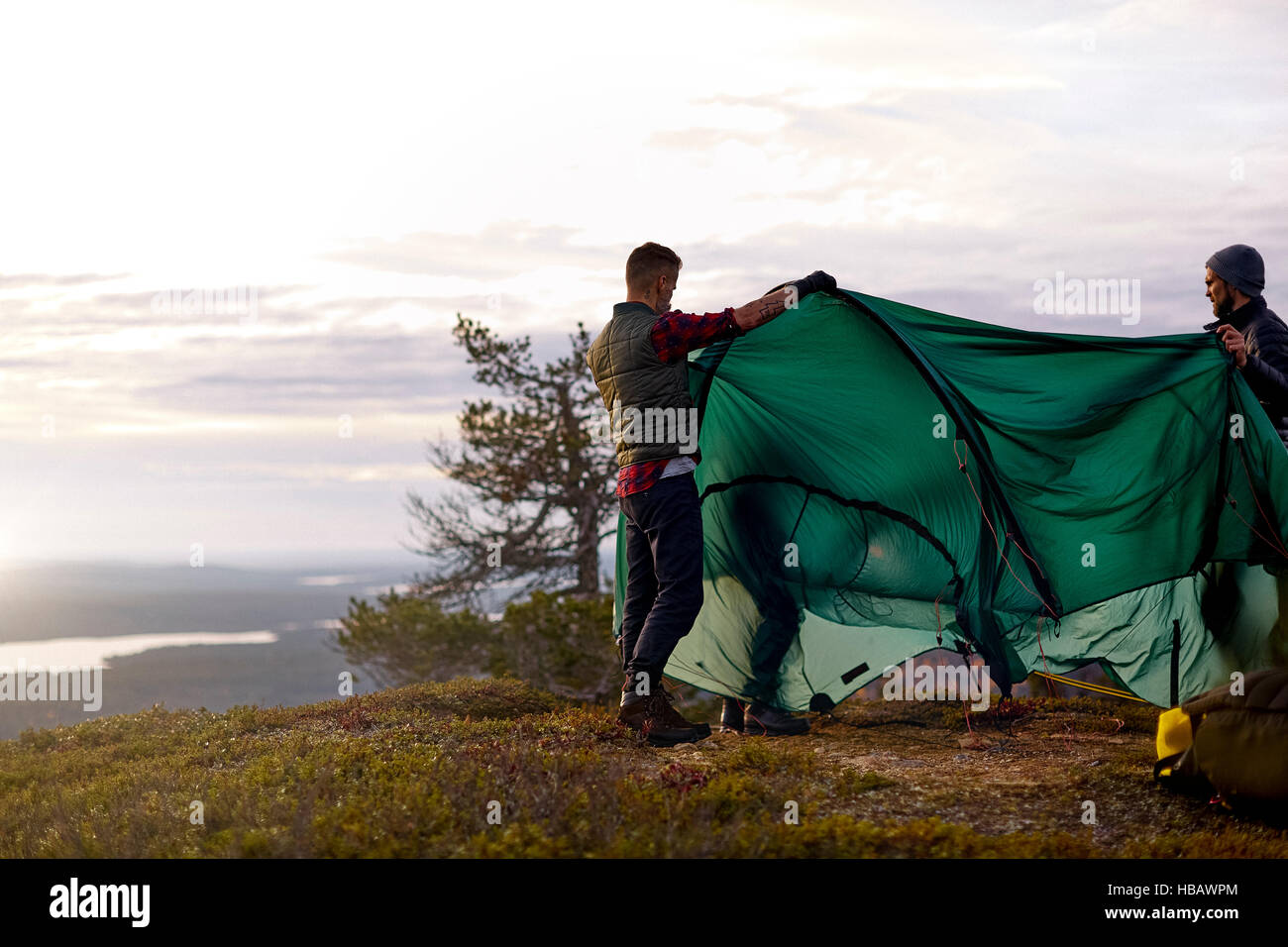 Hikers setting up tent on hilltop, Keimiotunturi, Lapland, Finland ...