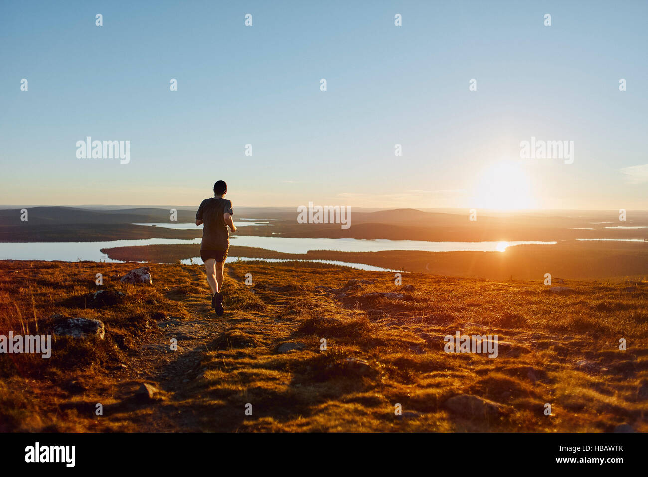 Man running on cliff top at sunset, Keimiotunturi, Lapland, Finland ...