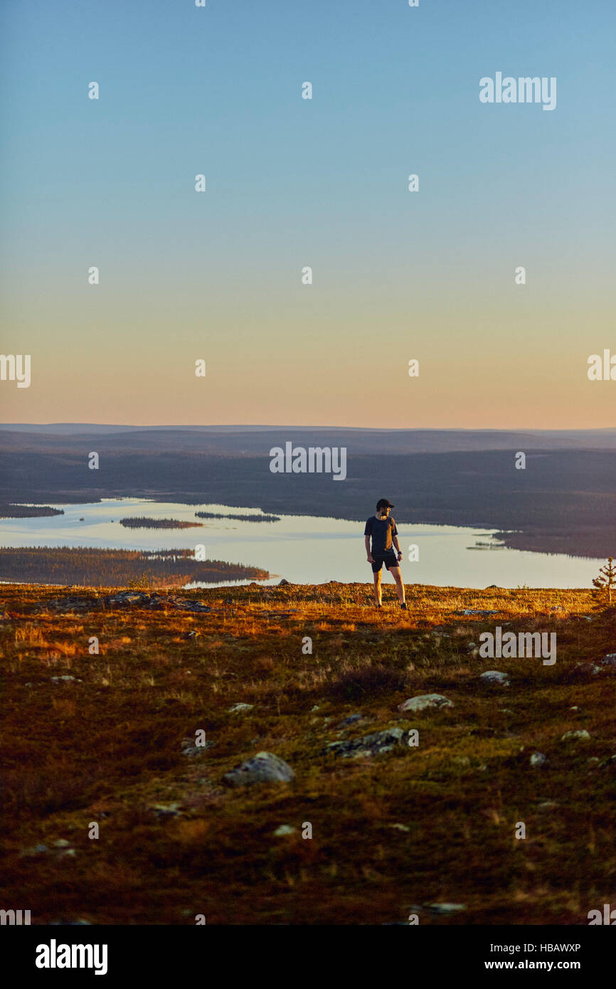 Man resting after running on cliff top at sunset, Keimiotunturi ...