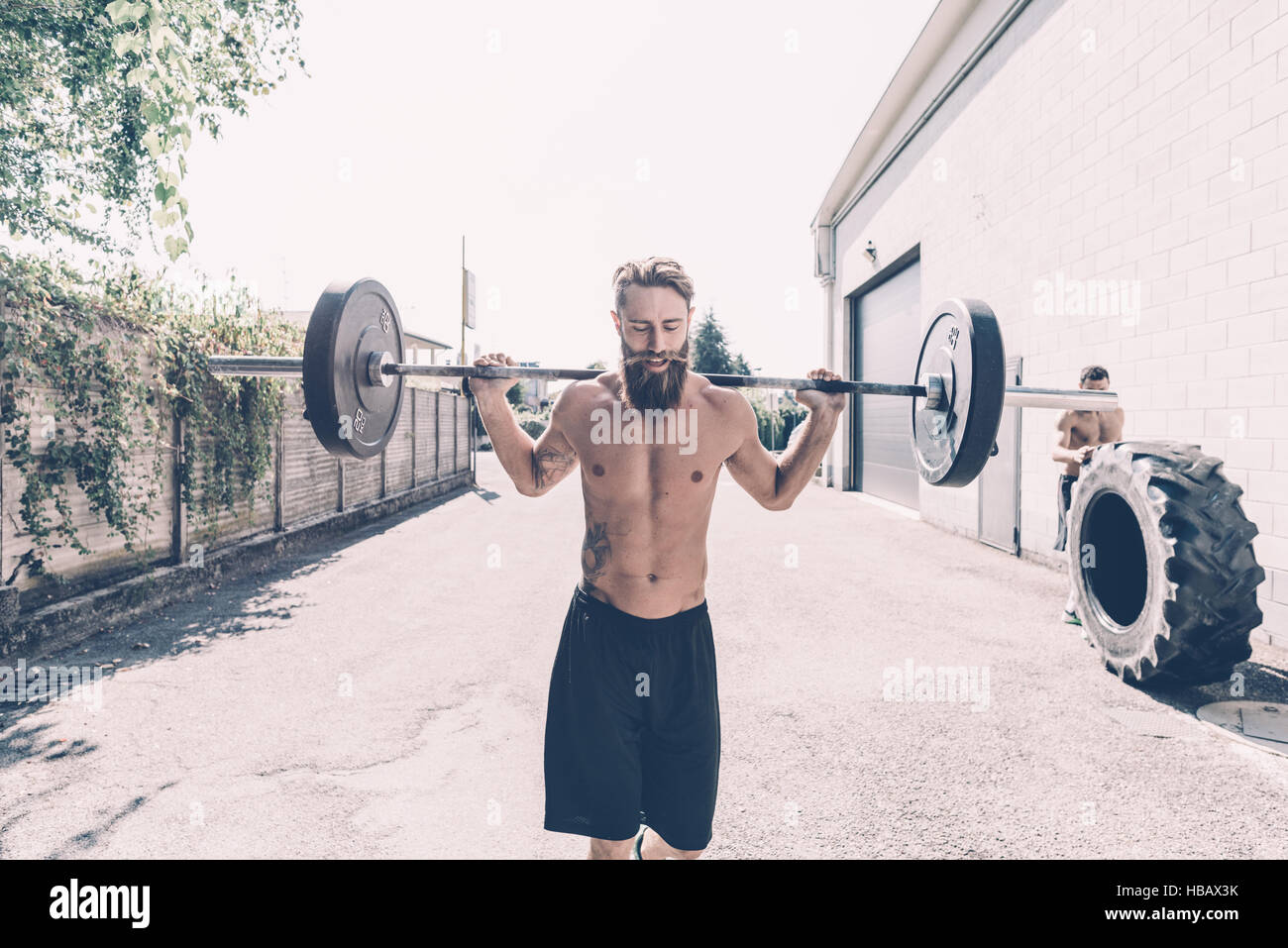 Young male cross trainer weightlifting barbell outside gym Stock Photo ...