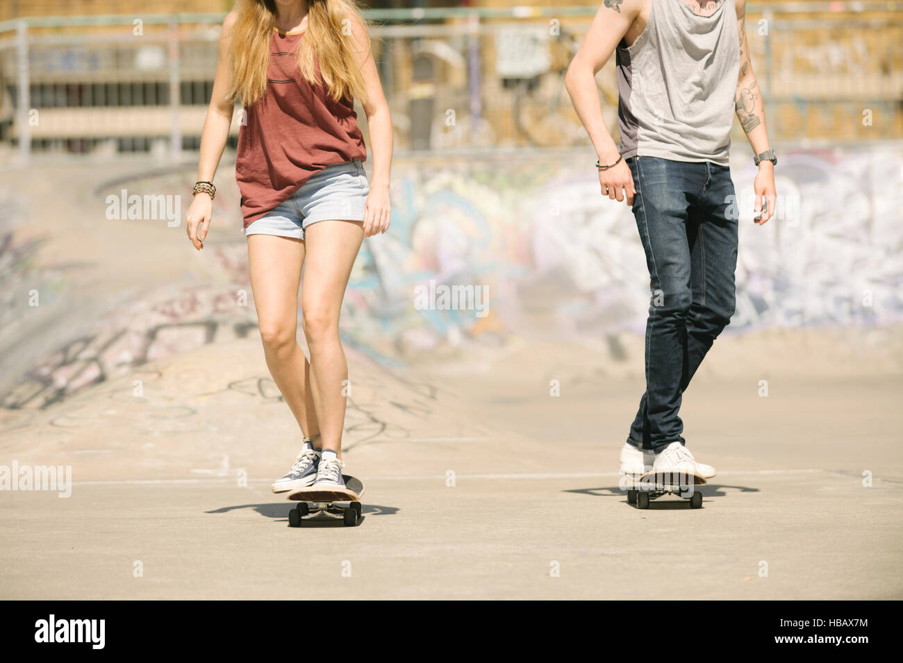 Neck down view of female and male skateboarders skateboarding in ...