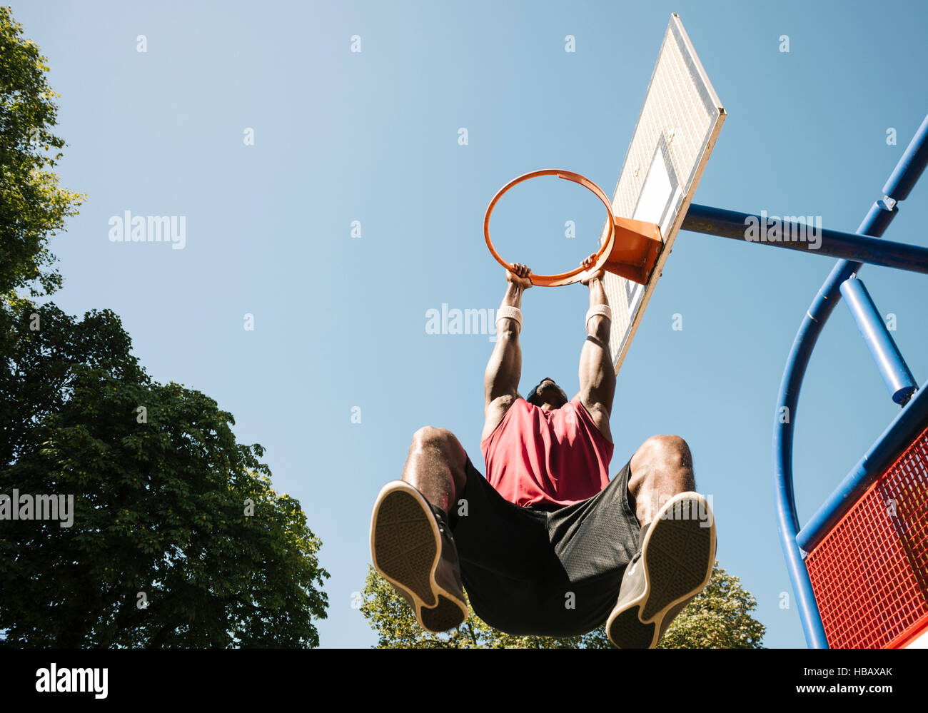 Young male basketball player hanging from basketball hoop Stock Photo ...