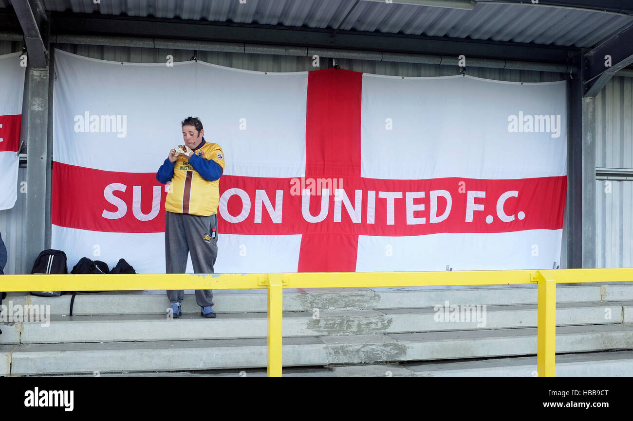 Fan eating a pie on terraces at Sutton United Football Club in Gander ...