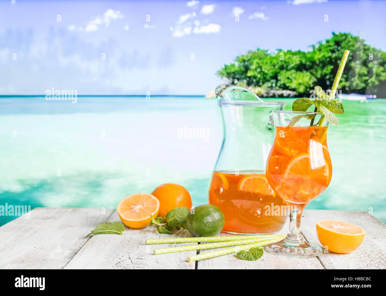 Glass of summer ice tea drink with lemon on the beach against the sea ...