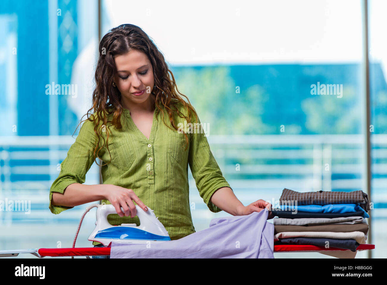 Young woman ironing clothing on board Stock Photo - Alamy