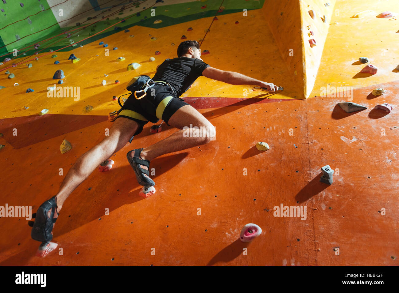 Active man climbing up the wall Stock Photo - Alamy