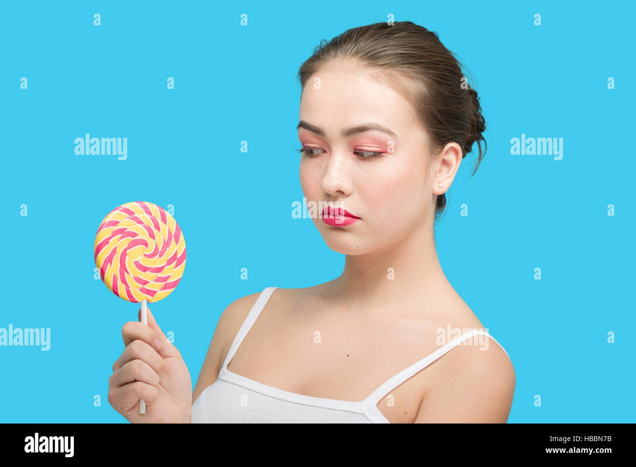 sad girl looking at candy on blue background Stock Photo - Alamy