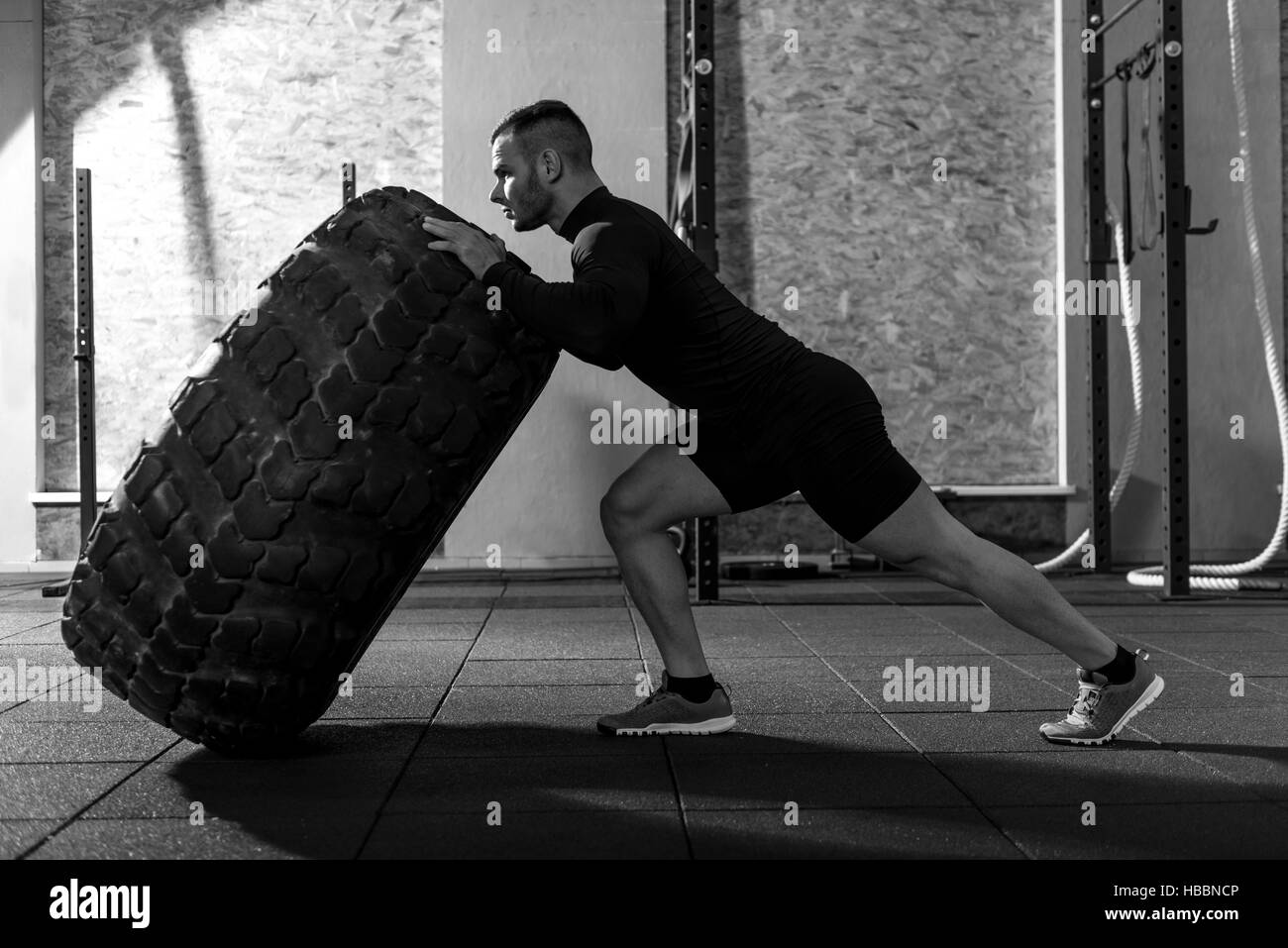 Strong handsome bodybuilder holding a huge tire Stock Photo - Alamy