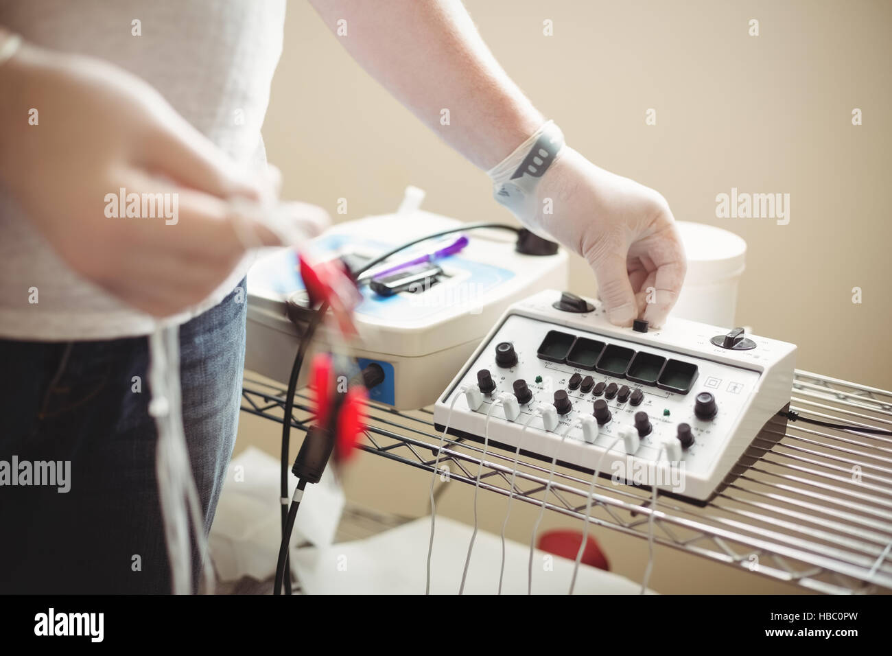 Mid section of a physiotherapist adjusting the electro dry needling ...