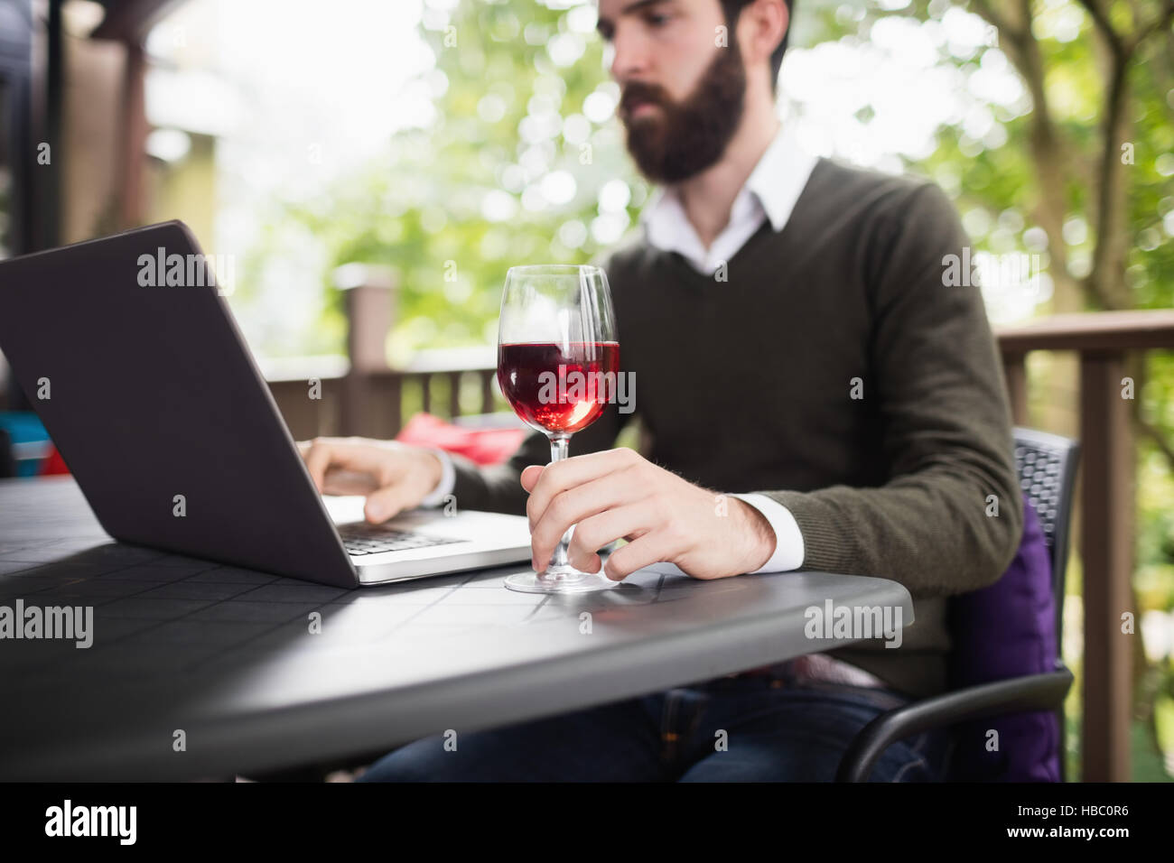 Man using laptop while having glass of wine Stock Photo - Alamy