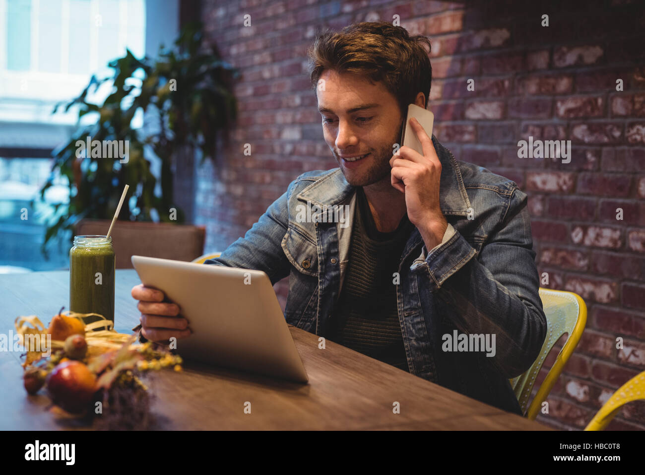 Man talking on mobile phone while using digital tablet Stock Photo - Alamy