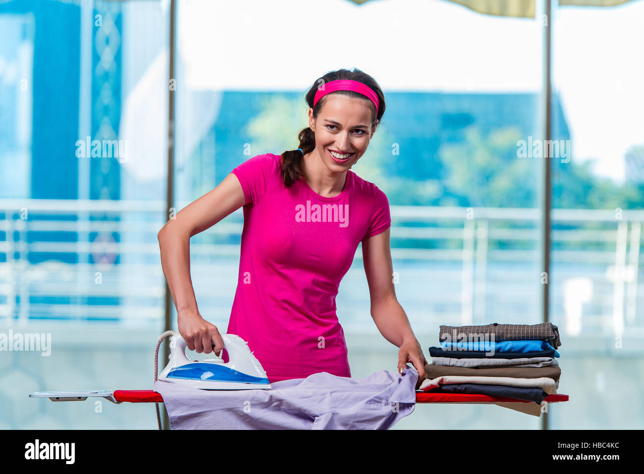 Young woman ironing clothing on board Stock Photo - Alamy