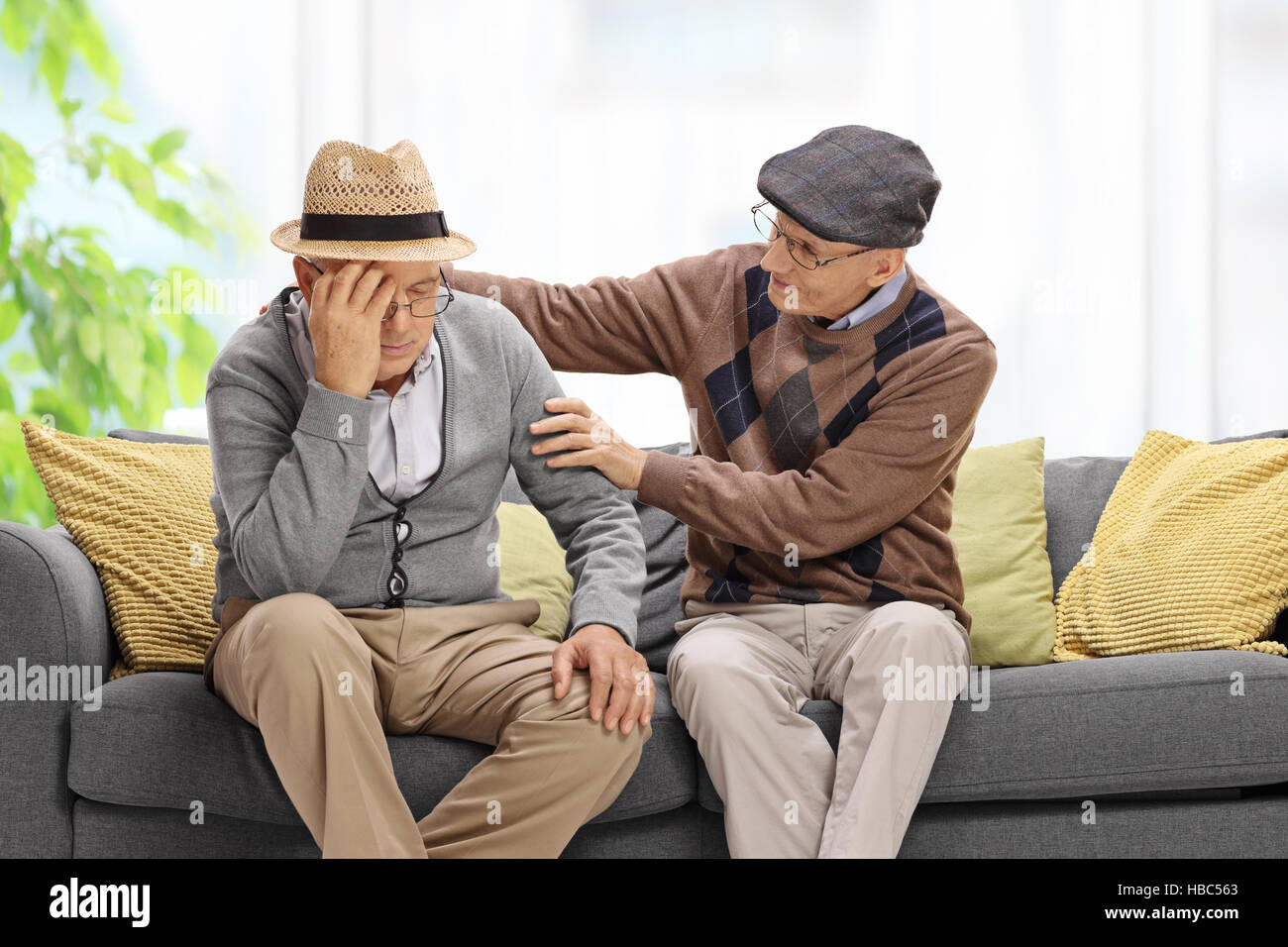 Senior sitting on a sofa and comforting another senior Stock Photo - Alamy