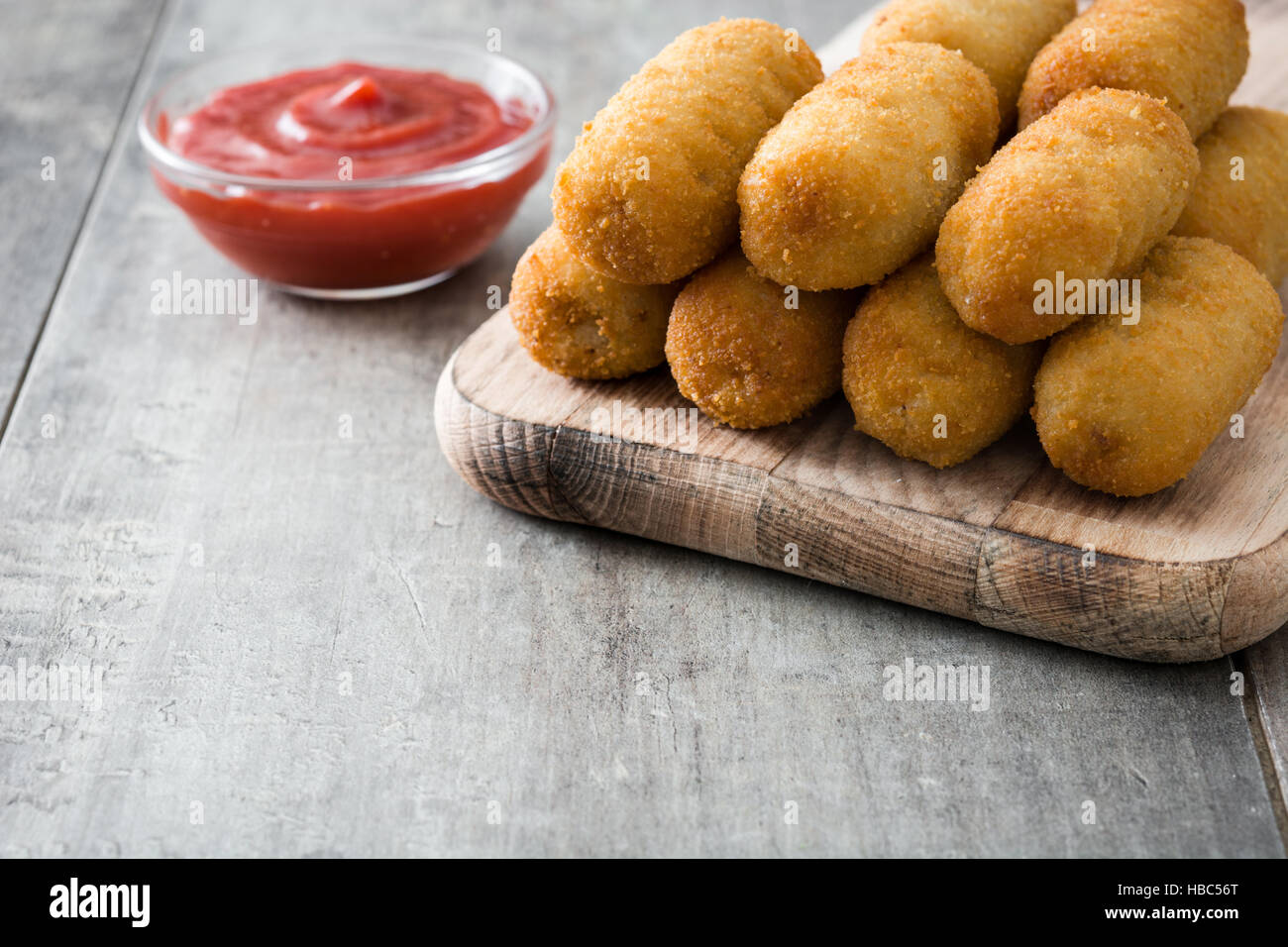 Traditional fried Spanish croquetas (croquettes) with ketchup on wooden ...