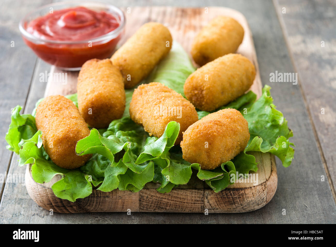 Traditional fried Spanish croquetas (croquettes) with ketchup on wooden ...