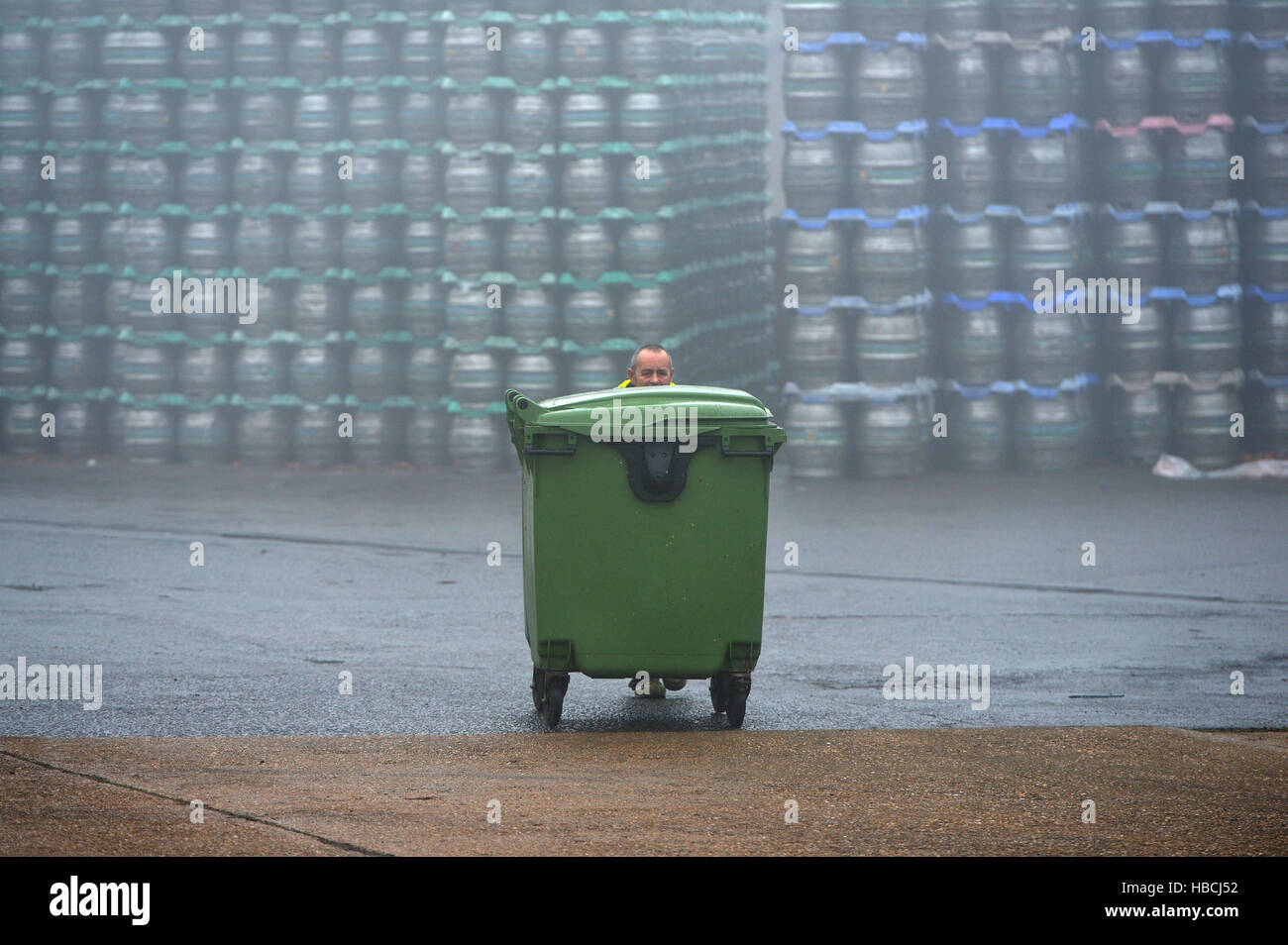 Man pushing wheelie bin in a brewery yard Stock Photo - Alamy