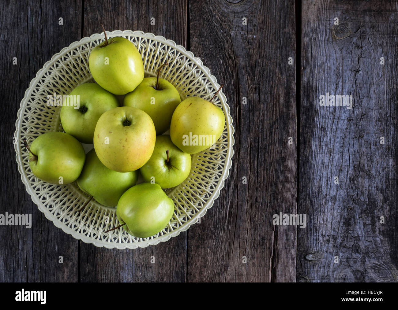 Overhead view of fresh green apples in plastic bowl placed on rustic ...