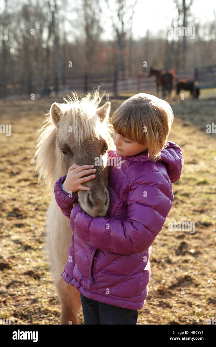 Young girl outdoors, hugging pony Stock Photo - Alamy