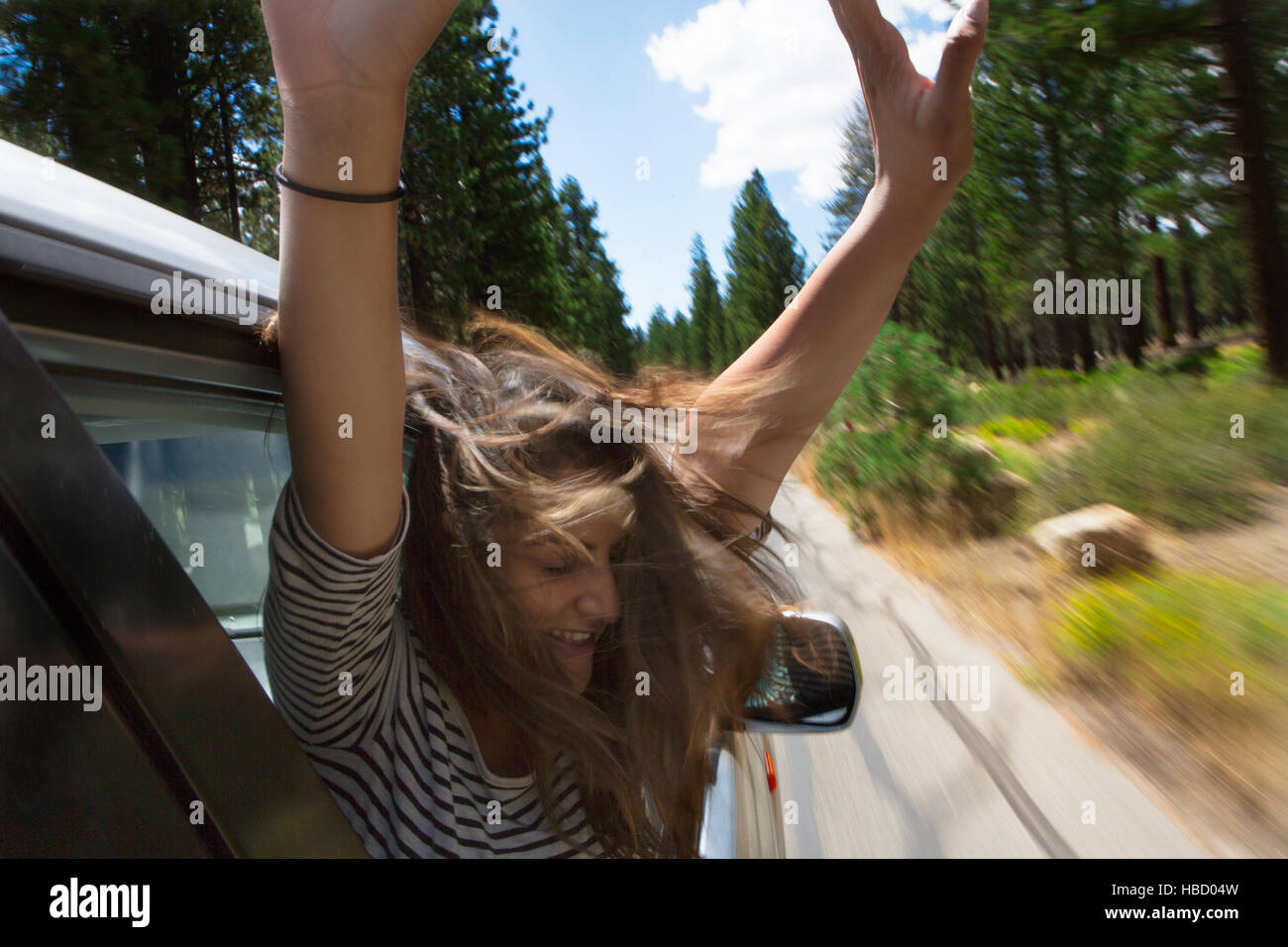 Young woman leaning out of moving car window, Mammoth Lakes, California ...