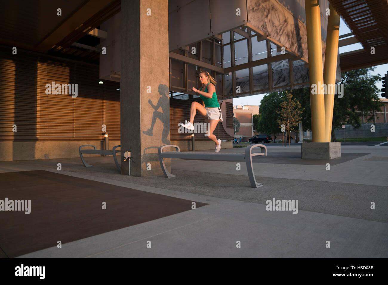 Young woman jumping over bench in urban environment Stock Photo - Alamy