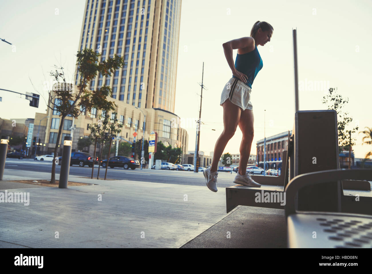 Young woman exercising outdoors, stepping up onto bench Stock Photo - Alamy