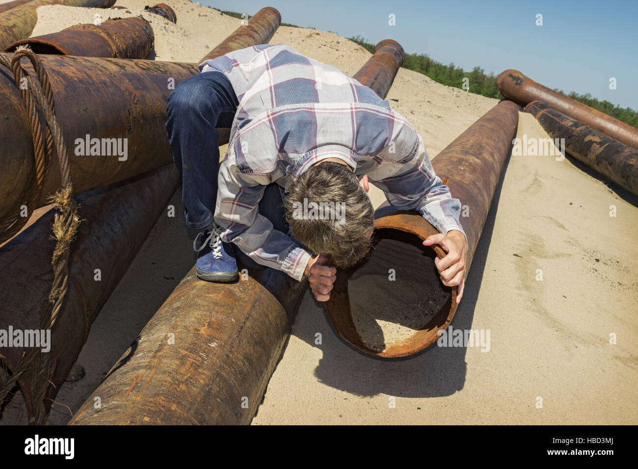 Curious young man looks into pipe Stock Photo - Alamy