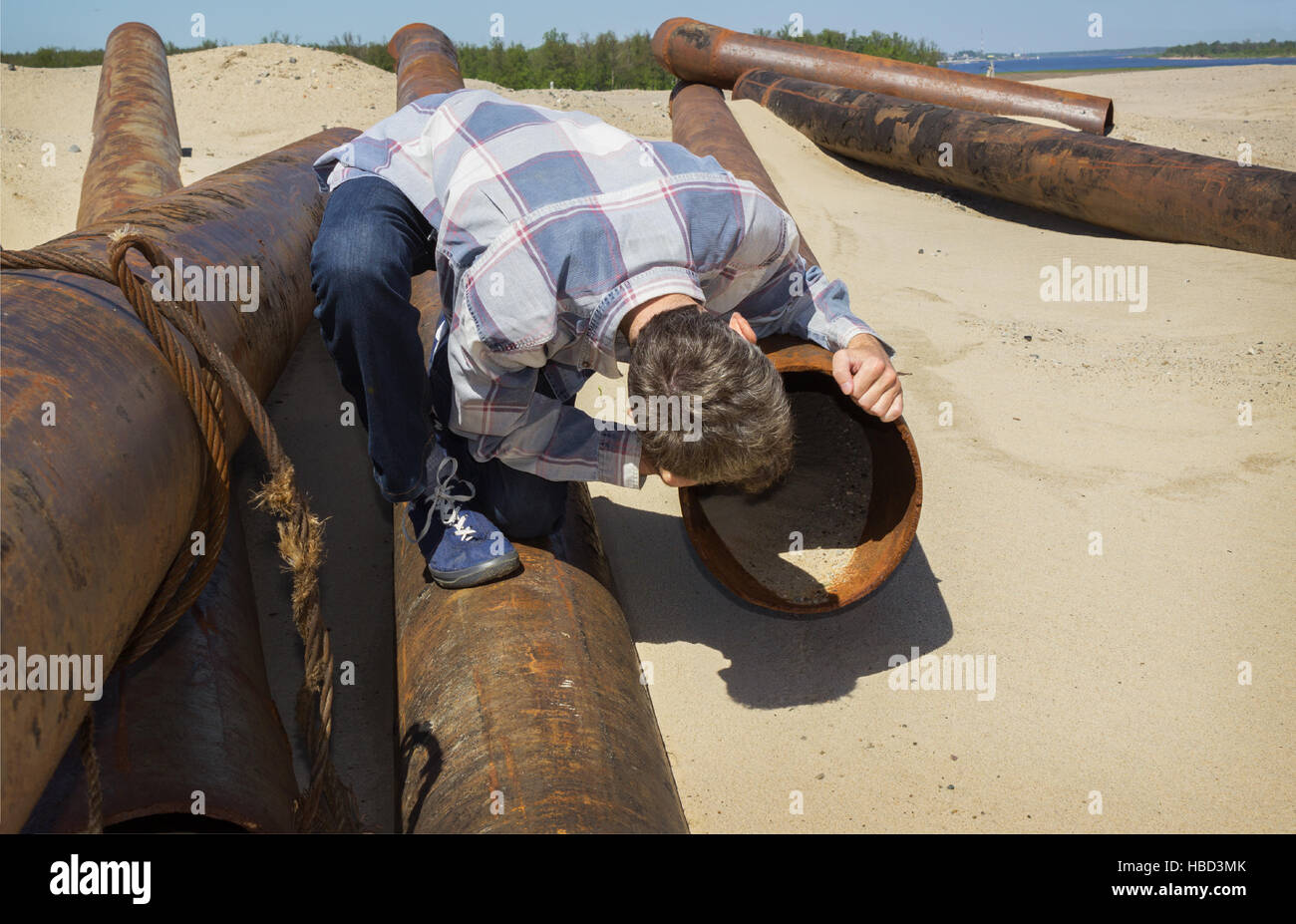 Very curious young man looks into pipe Stock Photo - Alamy
