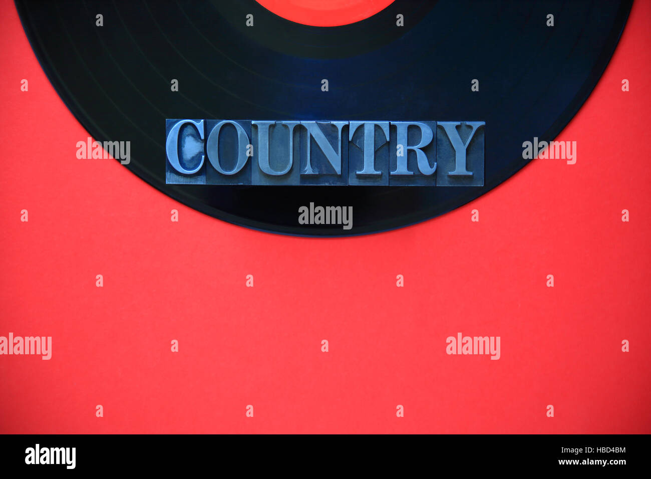 The word country in metal type on a black vinyl record on a red ...